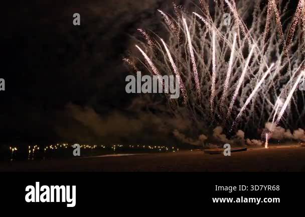 Fireworks display on the sandy beach near the ocean in the night sky ...