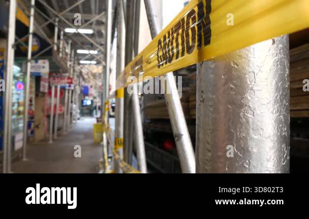 Caution yellow tape and scaffolding on pavement under construction in ...