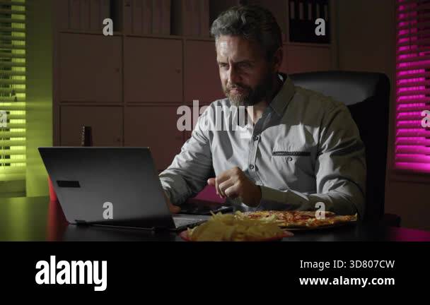 Business man eat pizza during a late night at office. An overworked man ...