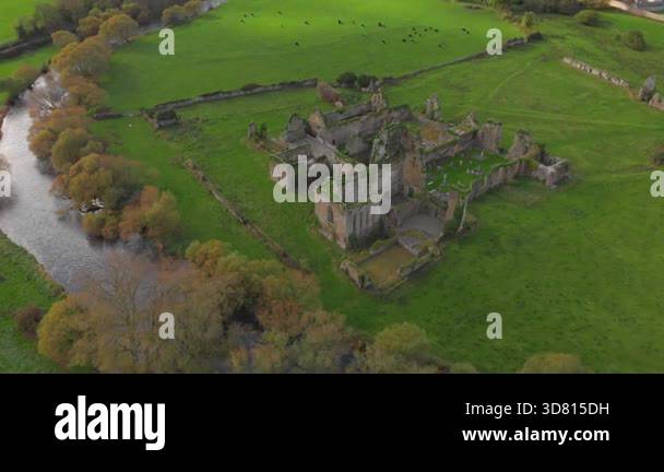 Ruins of an ancient structure lie peacefully in a lush landscape. Green ...
