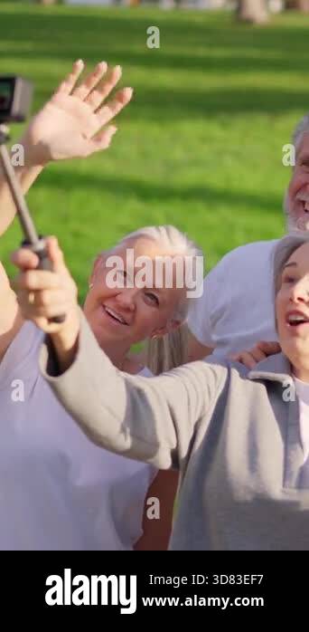 Group of joyful elderly people filming themselves with an action camera ...