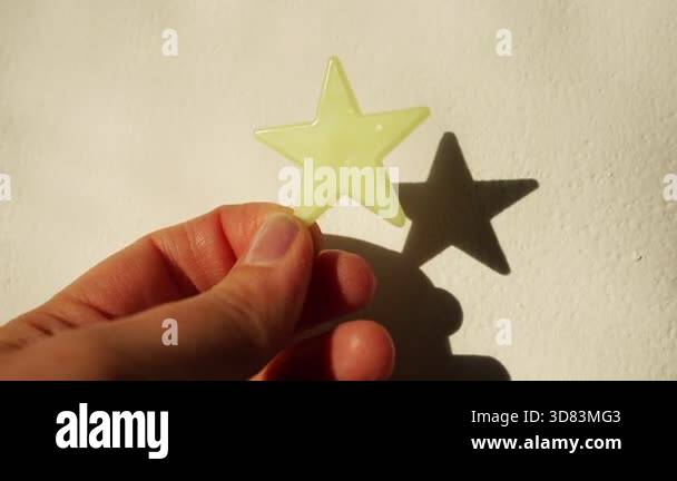 A hand gluing a luminescent five-pointed star, a self-adhesive toy, to ...
