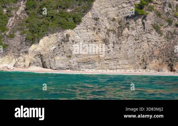 Sharp tall rocky cliffs visible above water, geological layers of rock ...