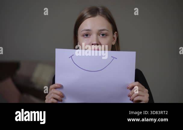 Young caucasian woman holding paper, hand-drawn smile covers mouth ...