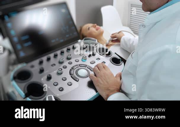 Doctor operating ultrasound machine while performing thyroid gland ...