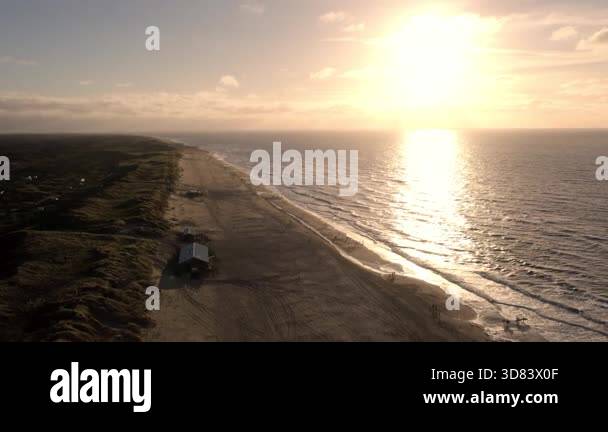 golden sunset over remote beach, drone panorama showing lone cabin on ...