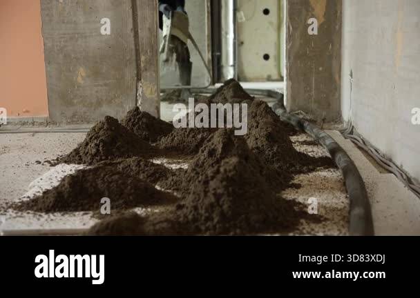Conical piles of dark mortar sit on white foam panels along a corridor ...