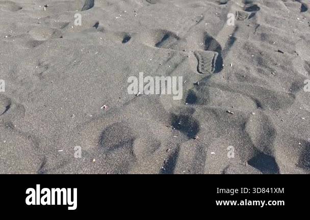Figure strolling along the dim sandy shore, creating a pathway of ...