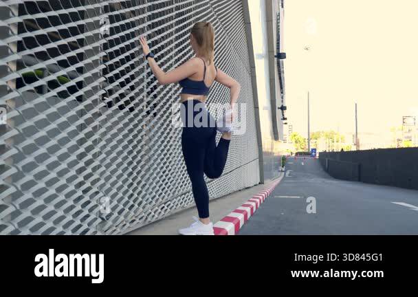 Young woman performs yoga exercise outdoors in city, active athlete ...