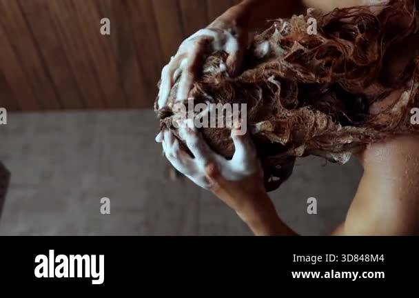 A young beautiful woman of European appearance washes her hair with ...