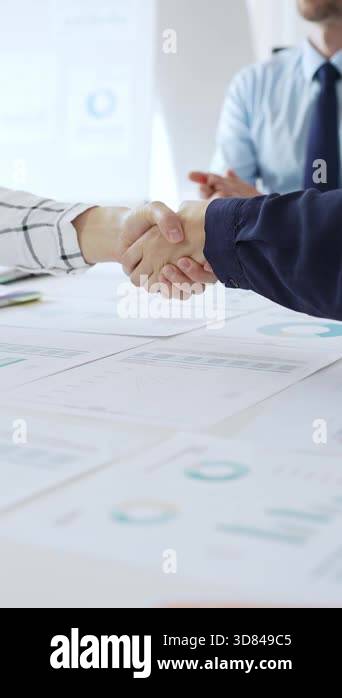 Business people partners shaking hands in office with financial charts ...