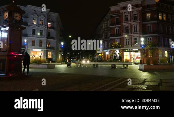 Nighttime footage of a European city street with moving cars, walking ...