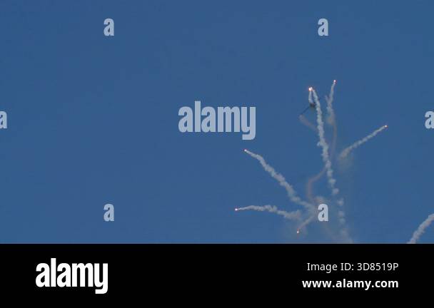 Military aircraft deploying multiple flares in sky during tactical ...