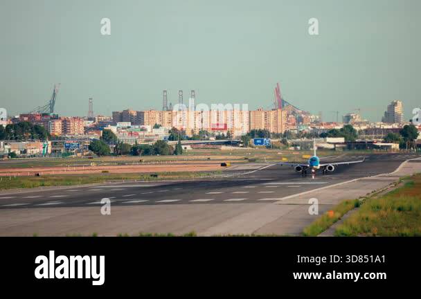 Passenger aircraft lifting off runway with city buildings and cranes in ...