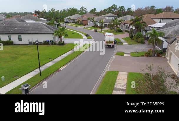 Trash truck picking up garbage bins on Florida city street curbside ...
