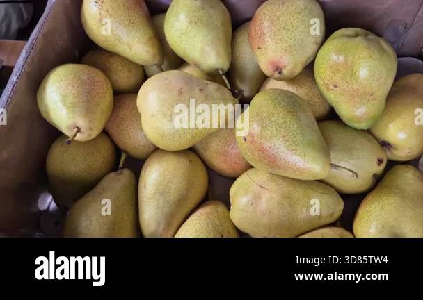 Ripe pears are placed in a carton for sale at a vegetable shop, showing ...
