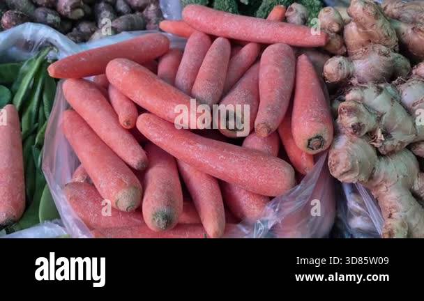 Orange carrots are stacked in a pile for sale, showing smooth skin and ...