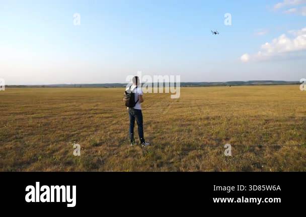 Pilot watches drone take off in vast field, highlighting the blend of ...