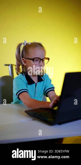 Vertical. Young student with glasses intently typing on a laptop ...