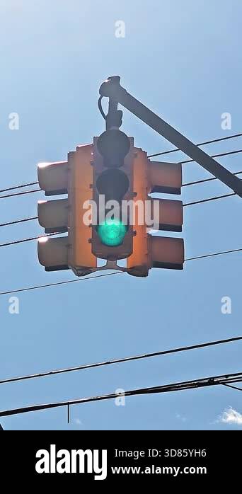 Traffic light with green signal hanging among cables on a bright sunny ...