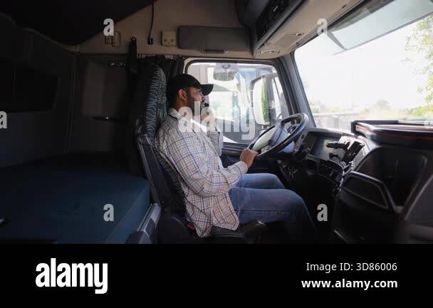 Young male lorry driver sitting inside a semi truck cabin behind the ...