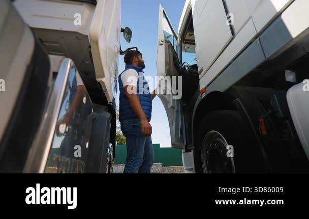 Professional male driver with a beard walking up to a large white truck ...