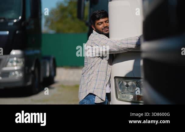 Cheerful long haul driver affectionately embracing his white semi truck ...
