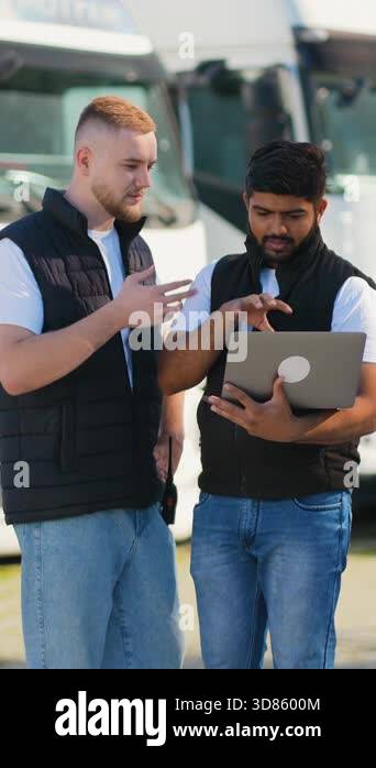 Two diverse male drivers standing in front of a semi truck, with one ...