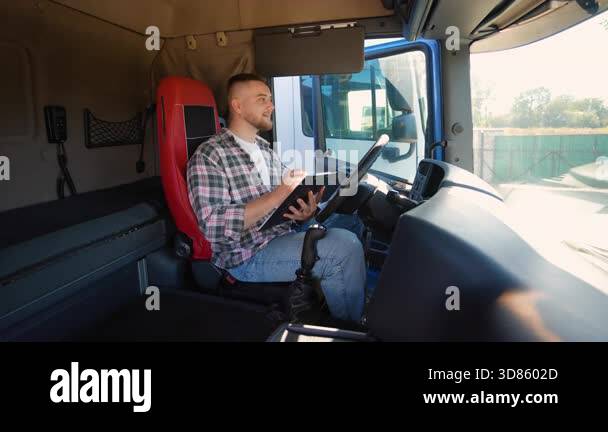 Confident male truck driver sitting in the cab of his semi truck ...