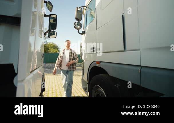 Long haul driver walking to his parked semi trailer truck, opening the ...