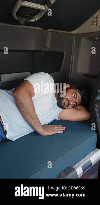 Young professional truck driver waking up from a nap in the sleeper ...