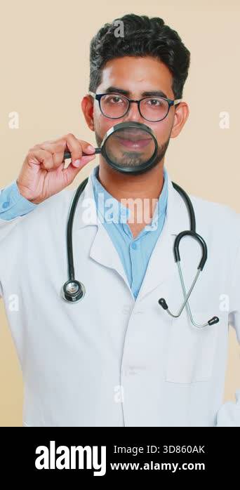 Happy Indian young doctor cardiologist man holding magnifier glass on ...