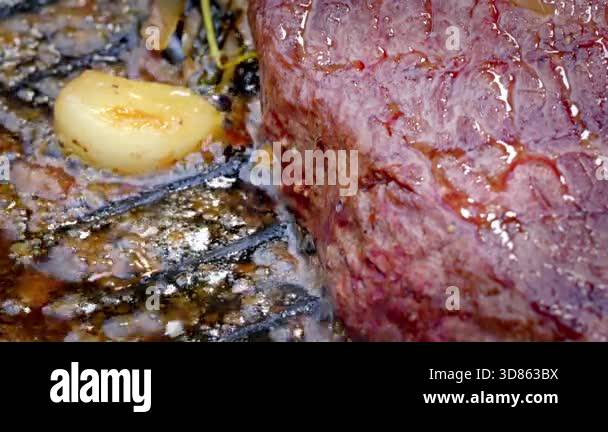 sizzling steak seared garlic in pan, juicy rare center glistening with ...