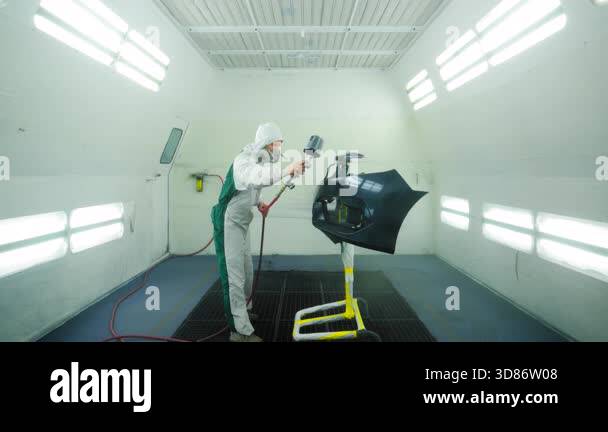 Auto body technician spray paint on car bumper inside a clean ...
