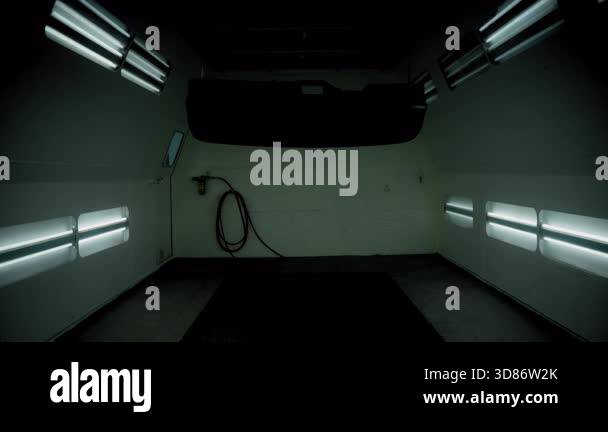 A freshly painted black car bumper hangs suspended inside a ...