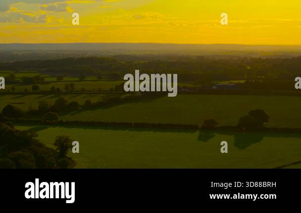 Peaceful countryside glowing under golden sunset above green farmland ...