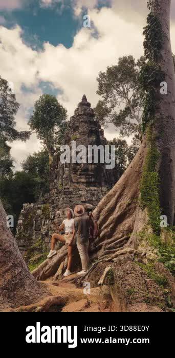 Young couple of travelers standing near giant tree roots in front of ...