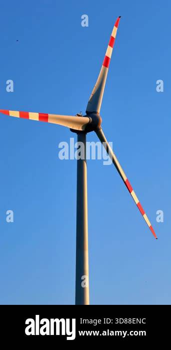 Wind turbine spinning under clear sky. A large wind turbine rotates ...