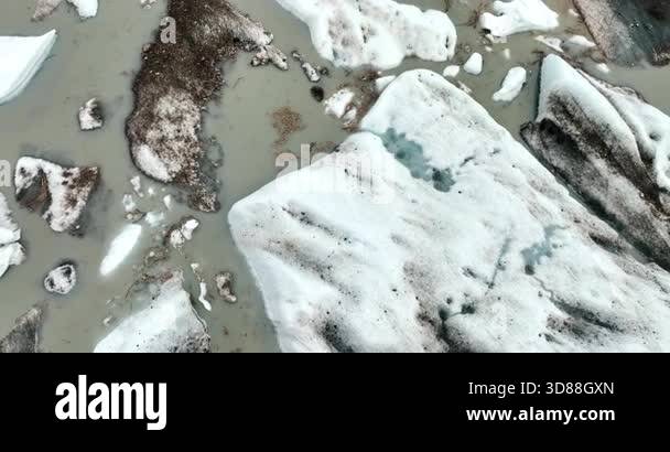 Melting boulders of ice in the grey waterscape of the river. Top view ...