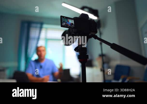 Camera on tripod set indoors. Display shows a man in blue uniform ...