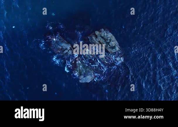 Deep blue color of water splashing by the rocks. Top view. Turbulent ...
