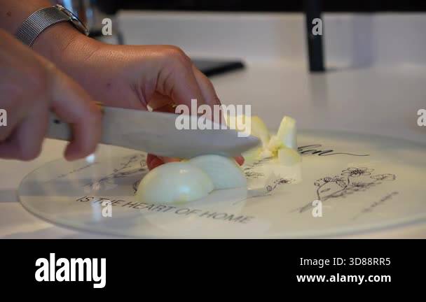 Close-up of hands slicing an onion with a kitchen knife on a cutting ...