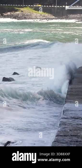 Ocean waves powerfully crash against a stone pier. This occurs in Porto ...
