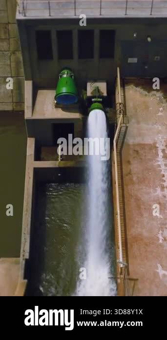 High angle view of stream of water flowing from pipe. Tilt up reveal of ...