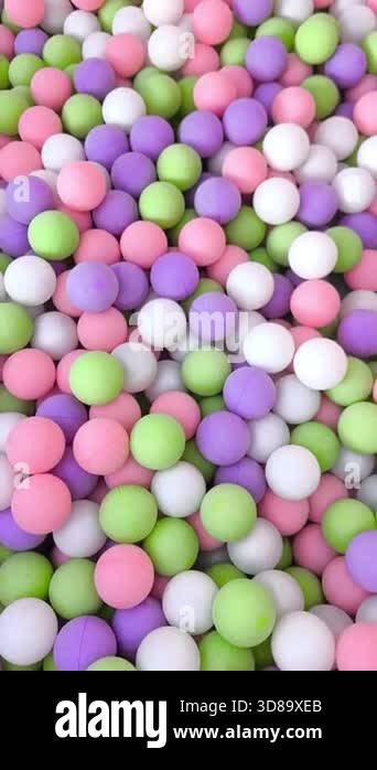 A multitude of plastic balls in pastel shades: purple, mint, pink, and ...