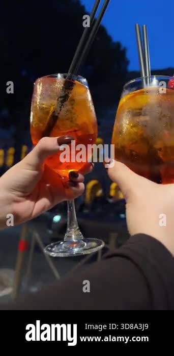 clink glasses of Aperol Glass with Aperol Spritz in a womans hand. Cold ...