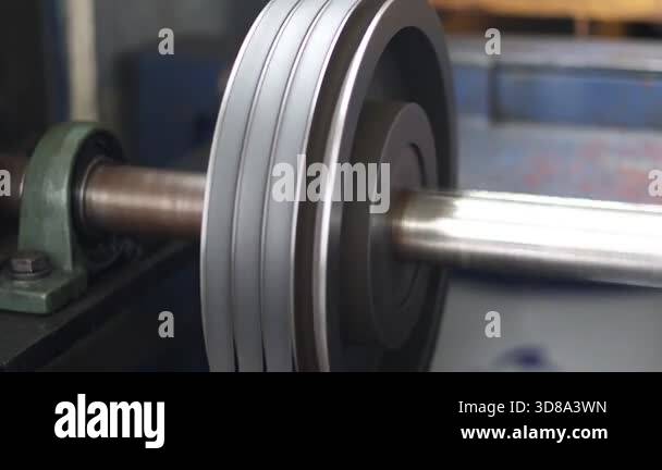 Close-up of a rotating industrial pulley system with dual V-belts on a ...