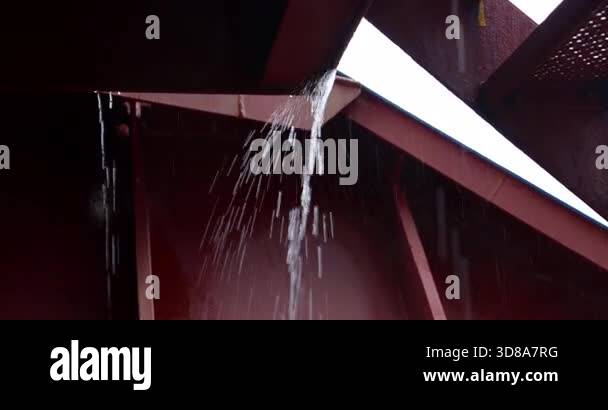 Stream of water swiftly flows down steel framework glimmering in faint ...