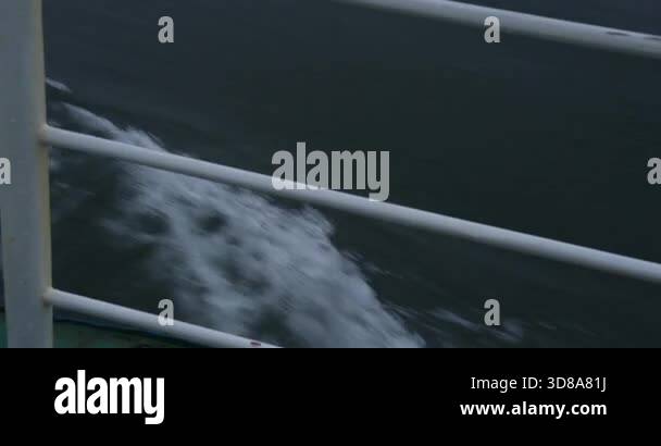 Steel hull cuts through water leaving foamy trail. Waves shimmer ...