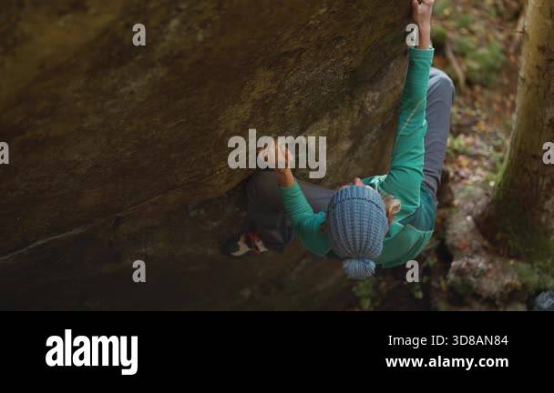 slow motion woman climber climbs crag bouldering reaching holds and ...
